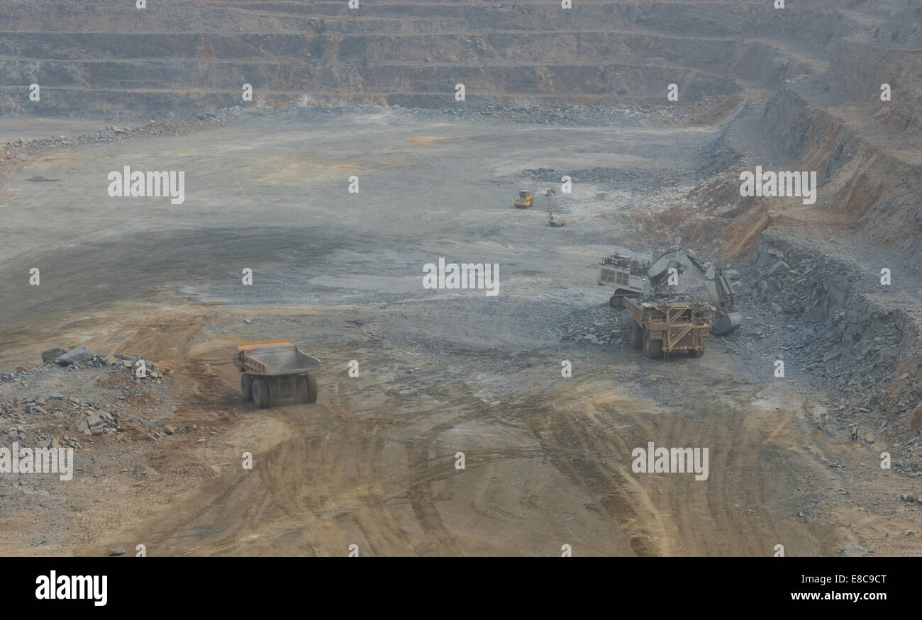 A big Liebherr excavator loads haul trucks with ore at a large open ...