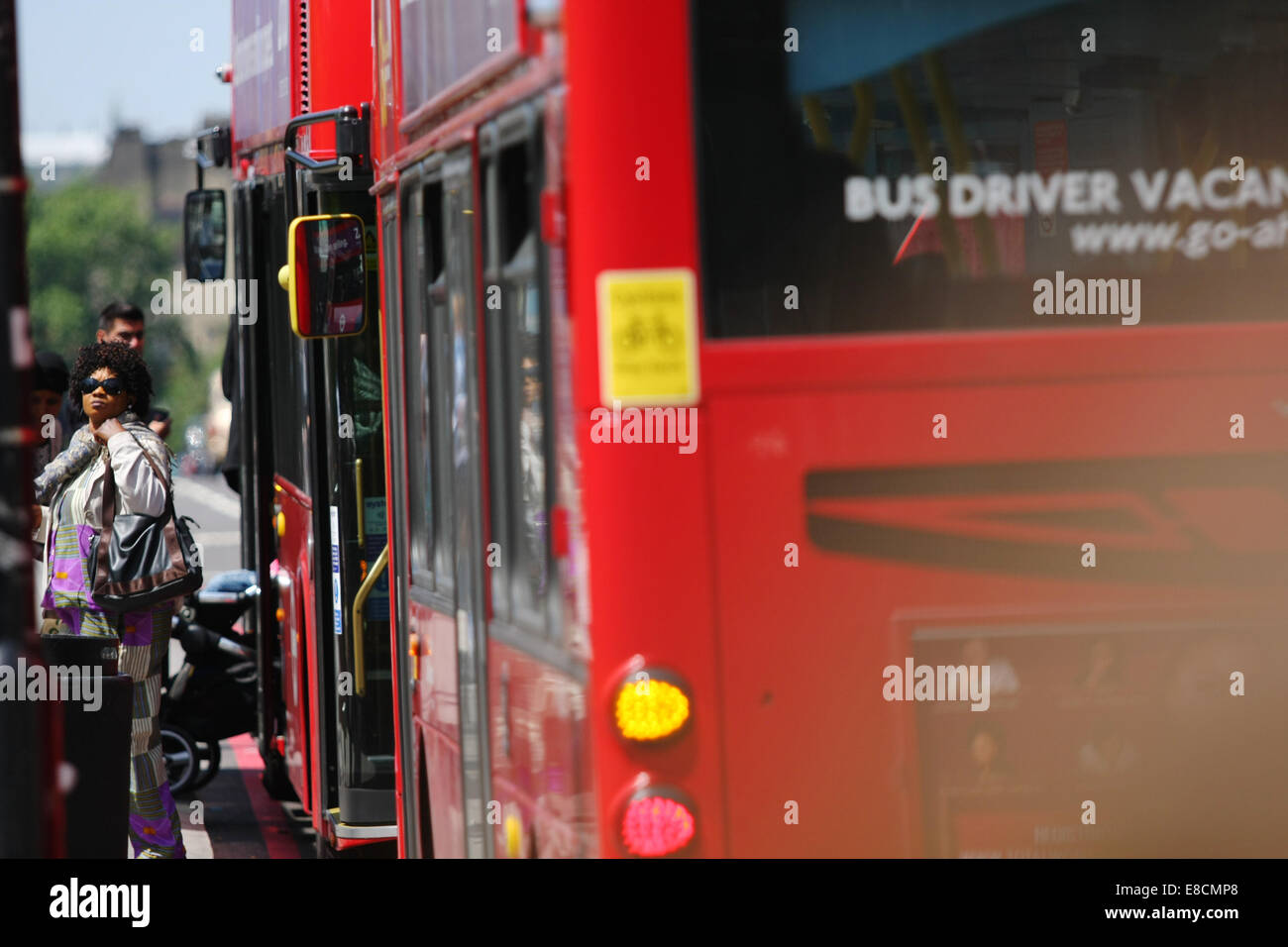 A red London bus waiting at a bus stop while passengers disembark Stock ...