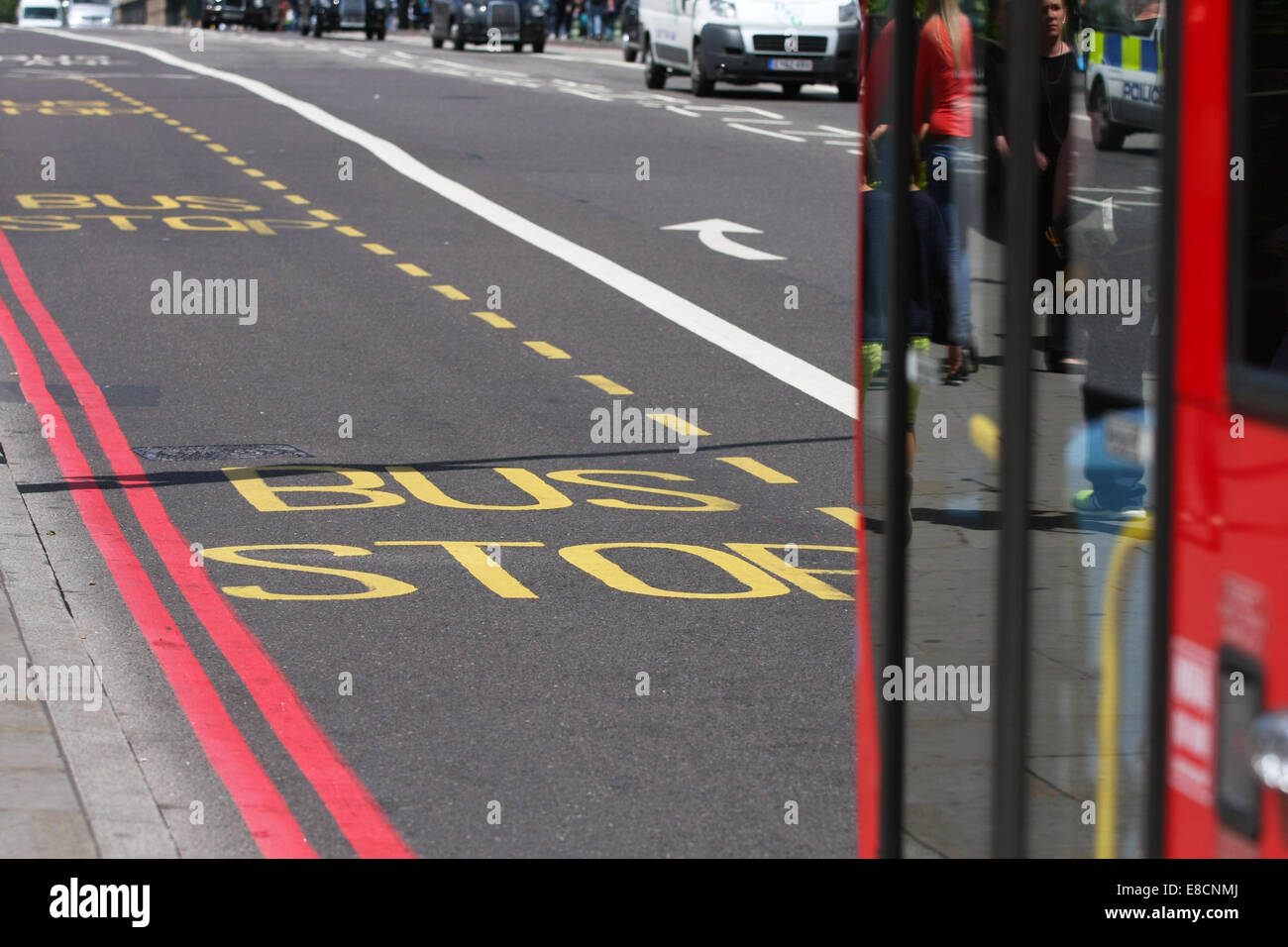 A red London bus traveling in a bus lane and approaching a bus stop in ...