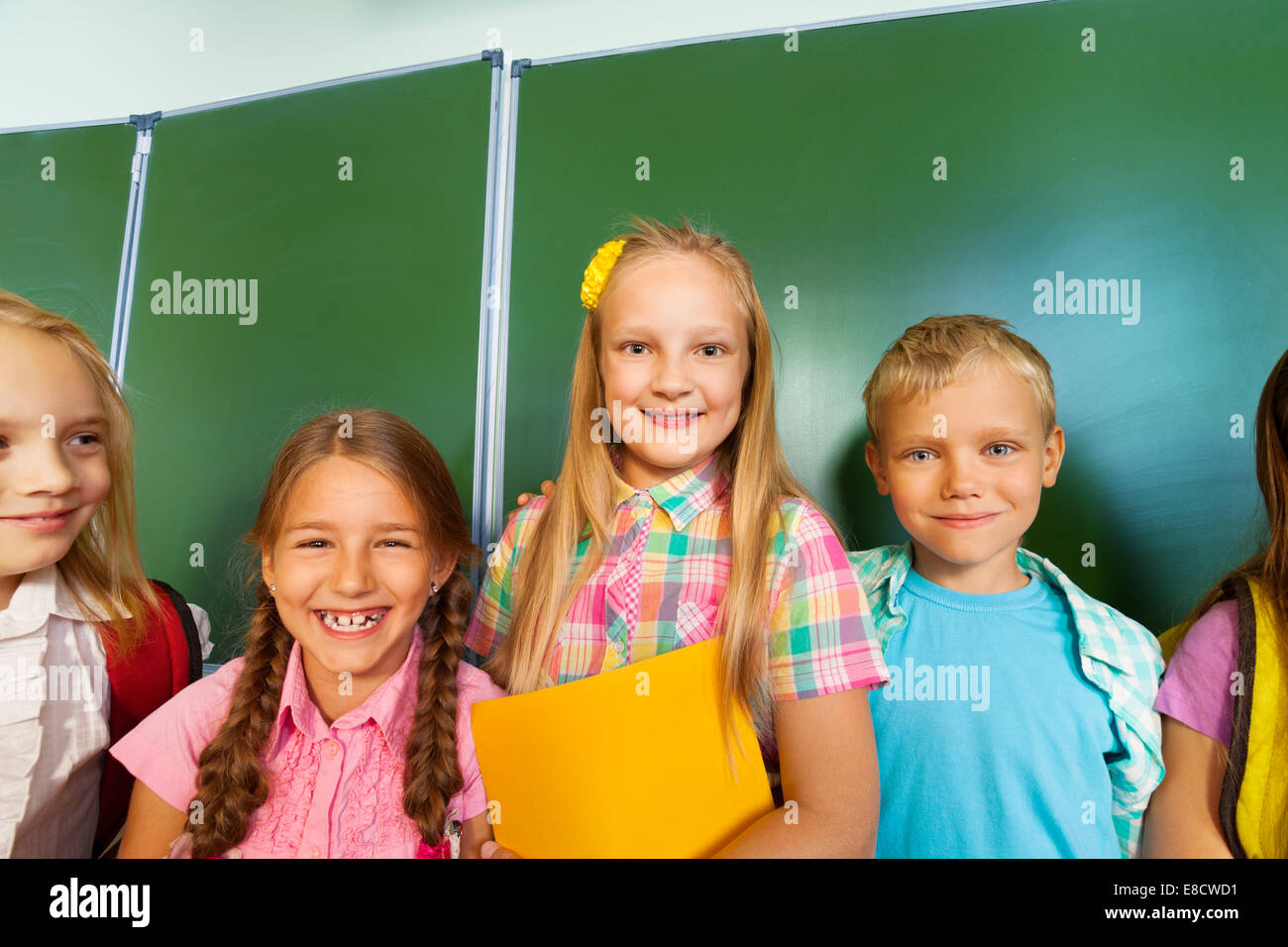 Four children stand with text books together Stock Photo - Alamy