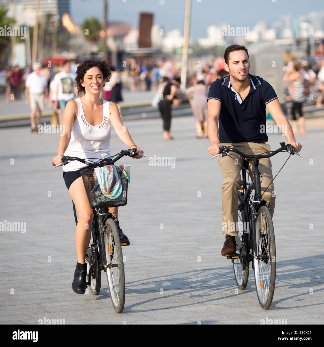 Two persons cycling on a city beach Stock Photo - Alamy