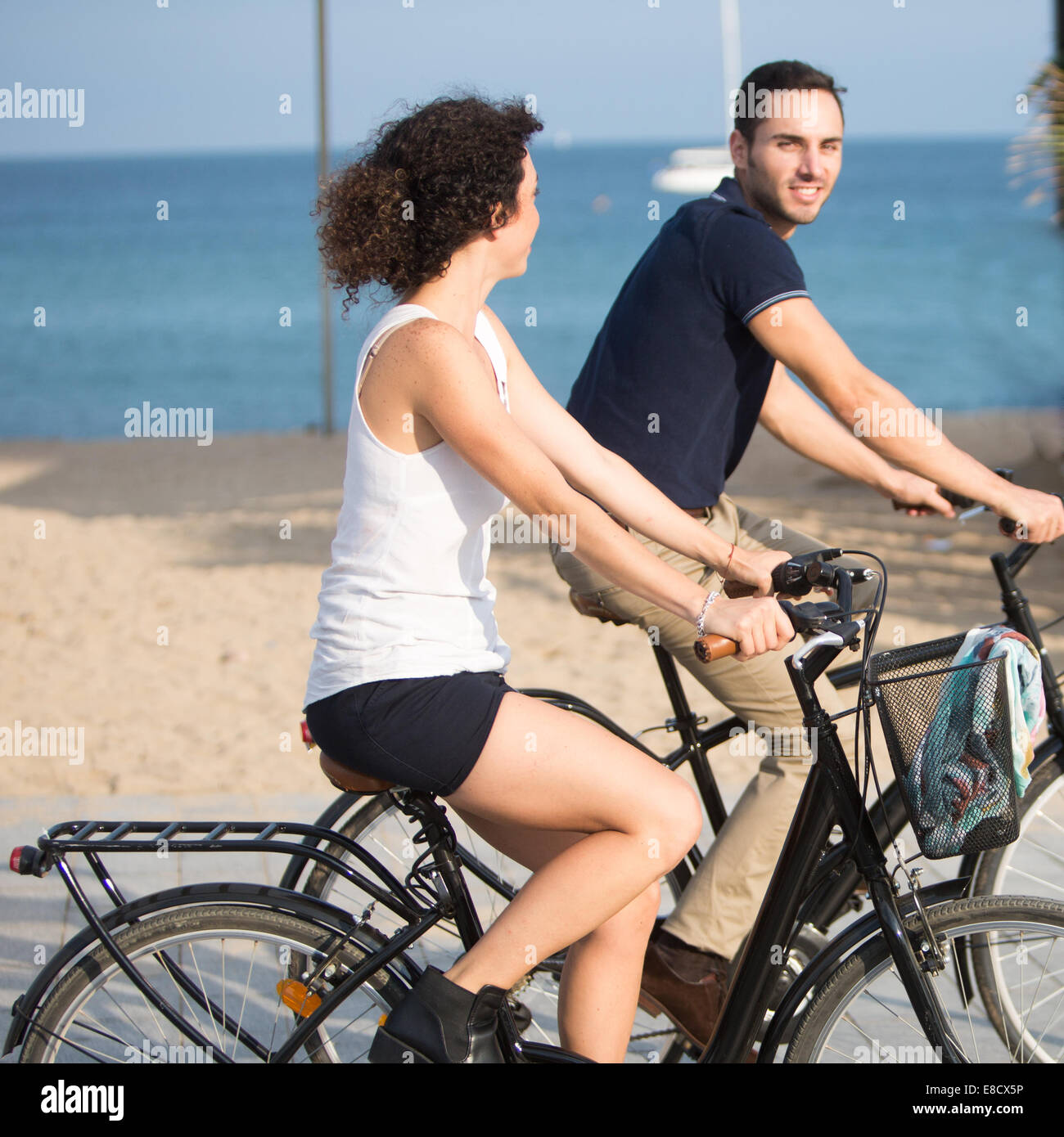 Two persons cycling on a city beach Stock Photo - Alamy