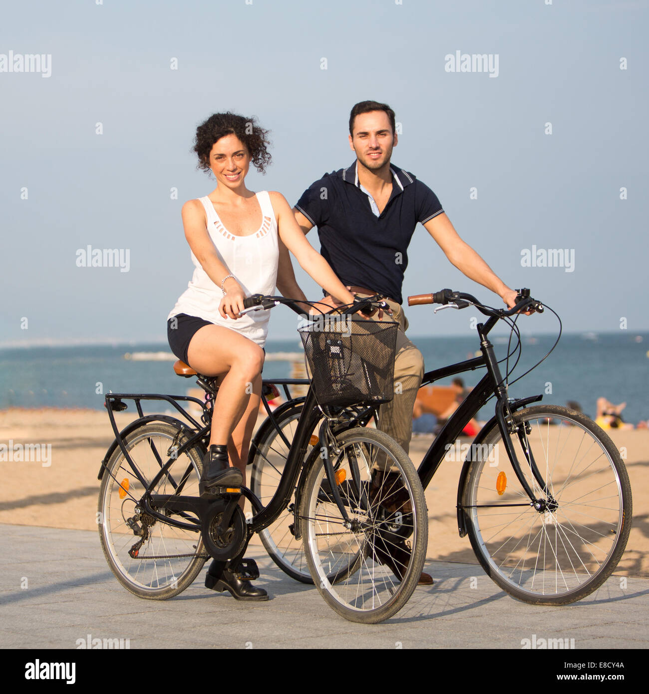 Two persons cycling on a city beach Stock Photo - Alamy