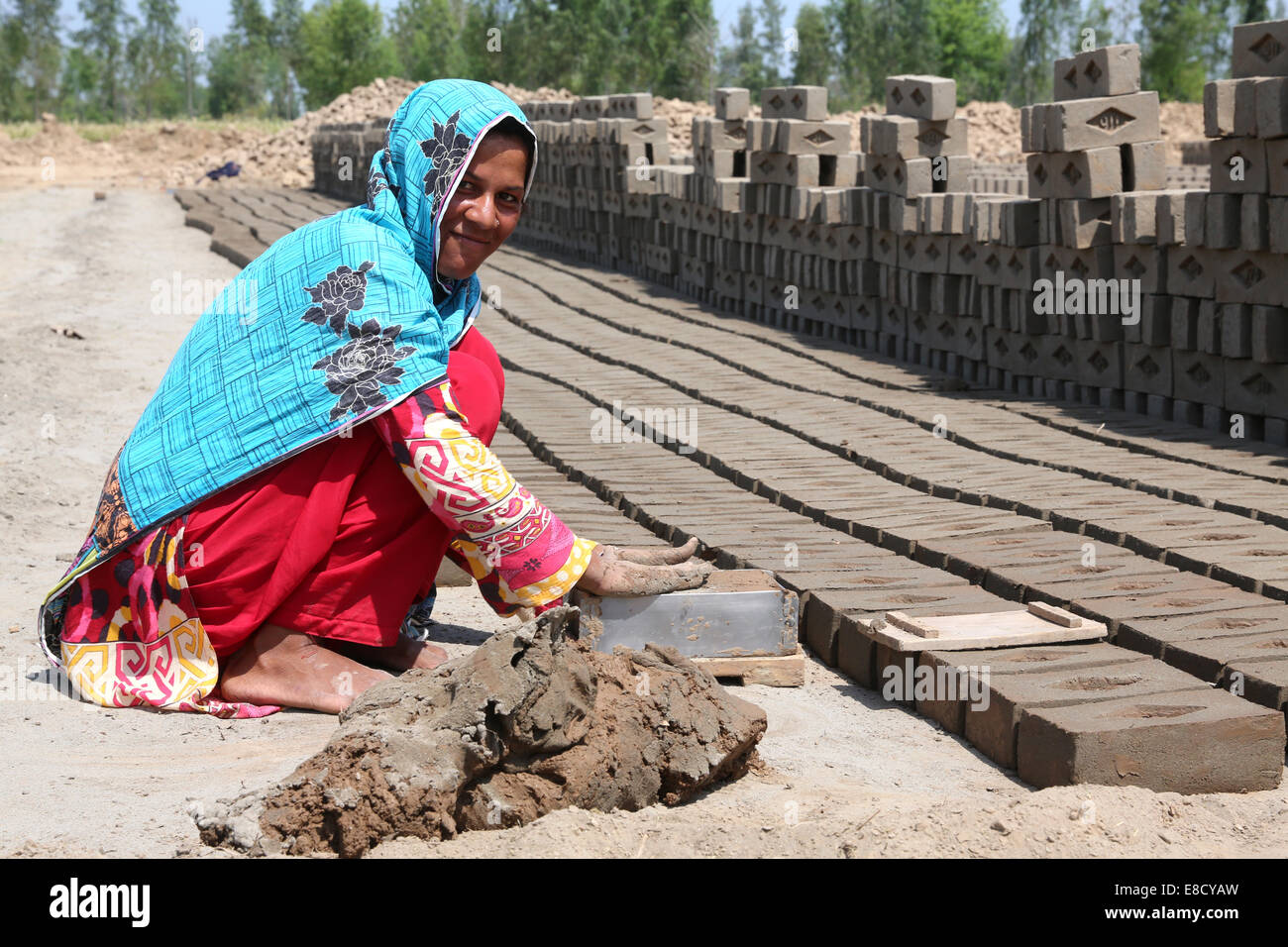 female brickyard worker (20 years) form clay bricks on a field of the ...