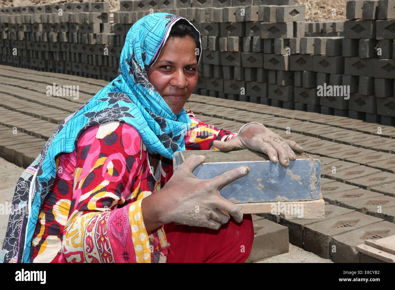 female brickyard worker (20 years) form clay bricks on a field of the ...