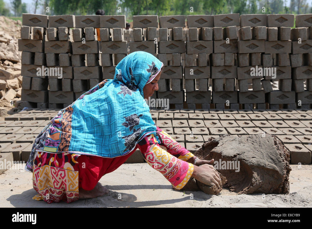 female brickyard worker (20 years) form clay bricks on a field of the ...