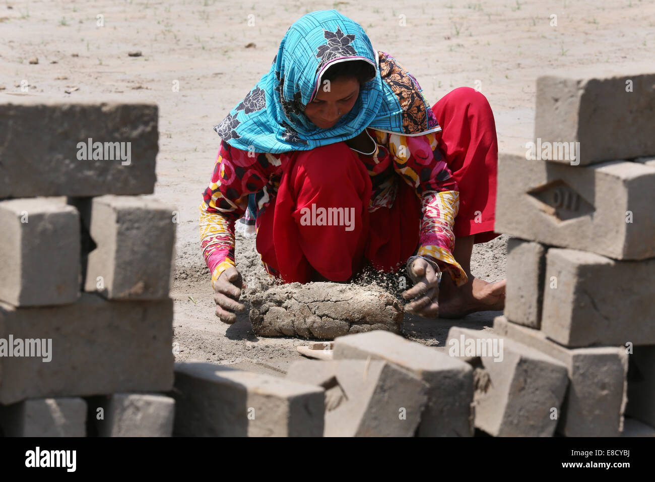 female brickyard worker (20 years) form clay bricks on a field of the ...