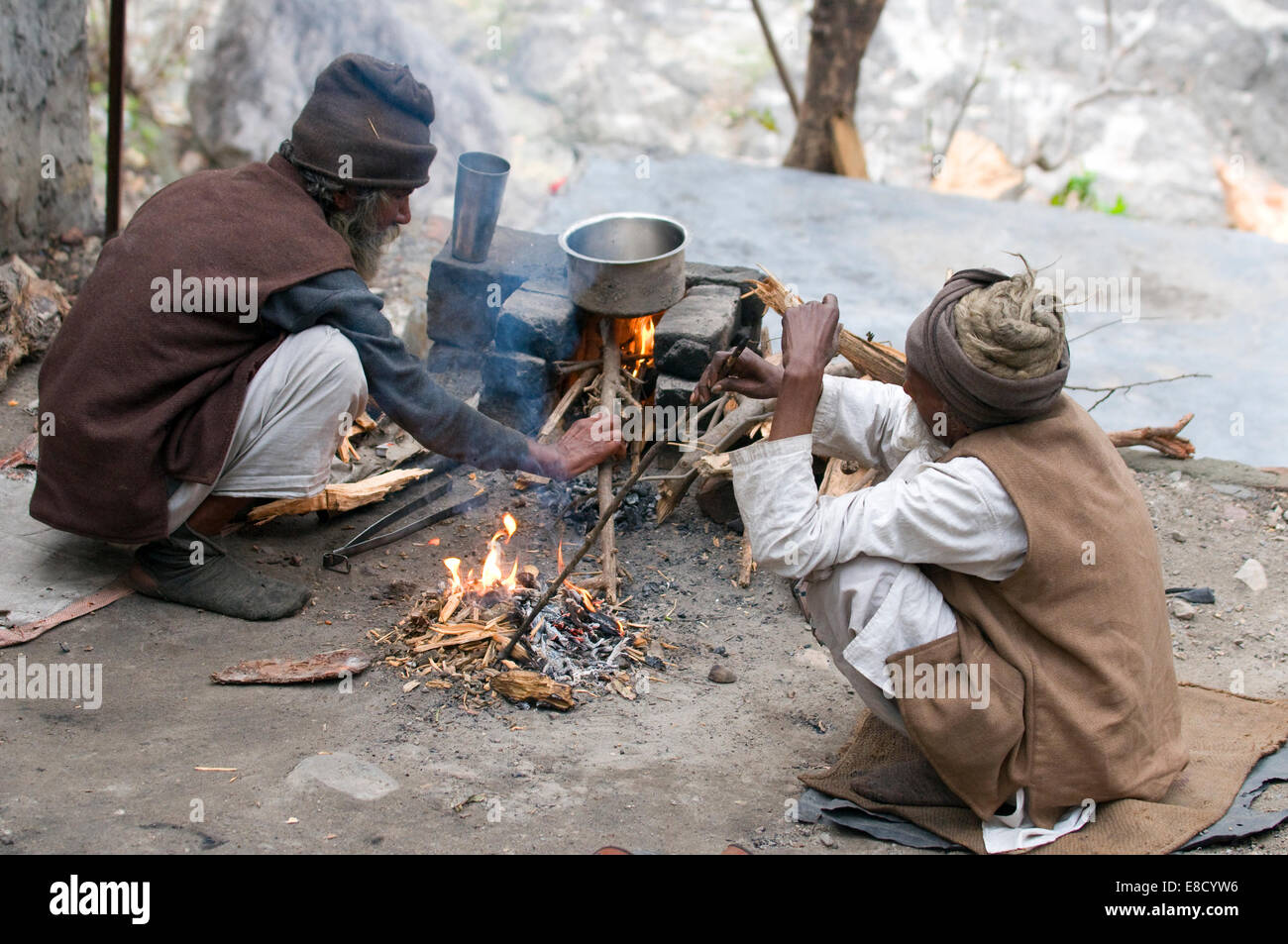Two old Sadhus friends sat on haunches by their fire (dhuni) cooking ...