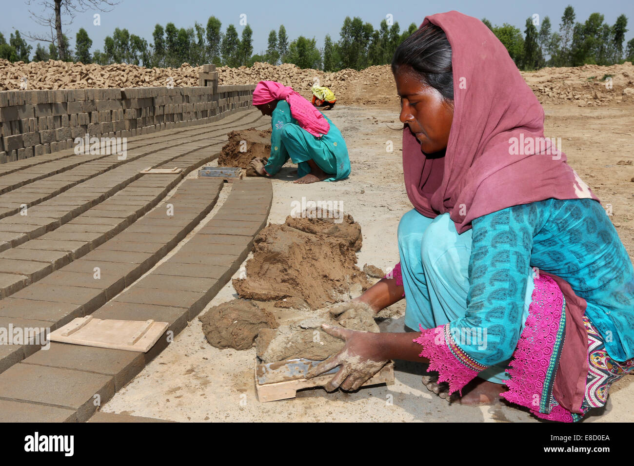 female brickyard worker (16 years) form clay bricks on a field of the ...