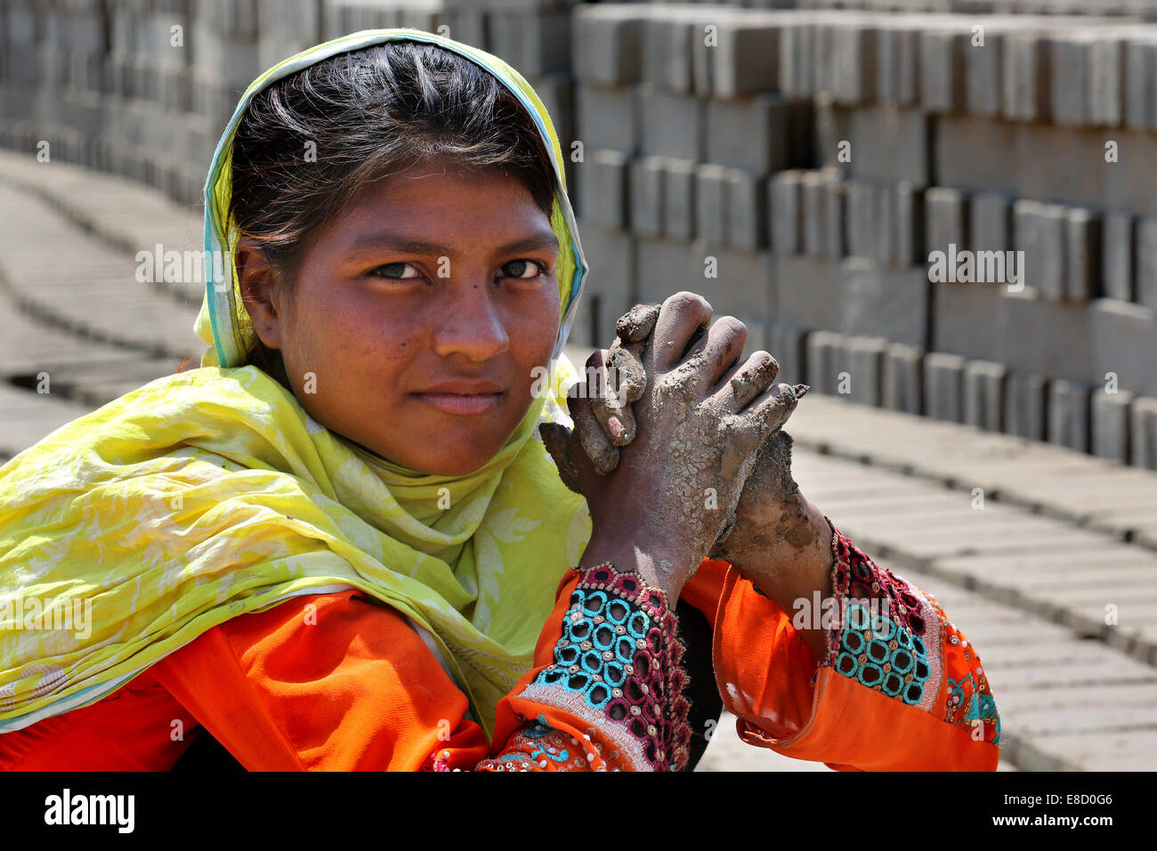 female brickyard worker (14 years old) form clay bricks on a field of ...
