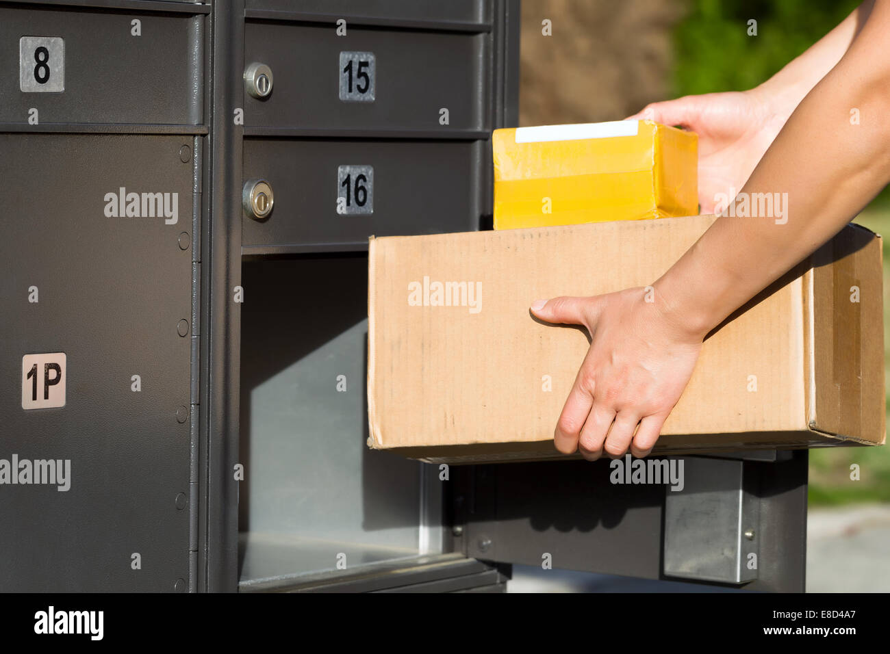 Horizontal image of female hands putting packages into postal mailbox ...