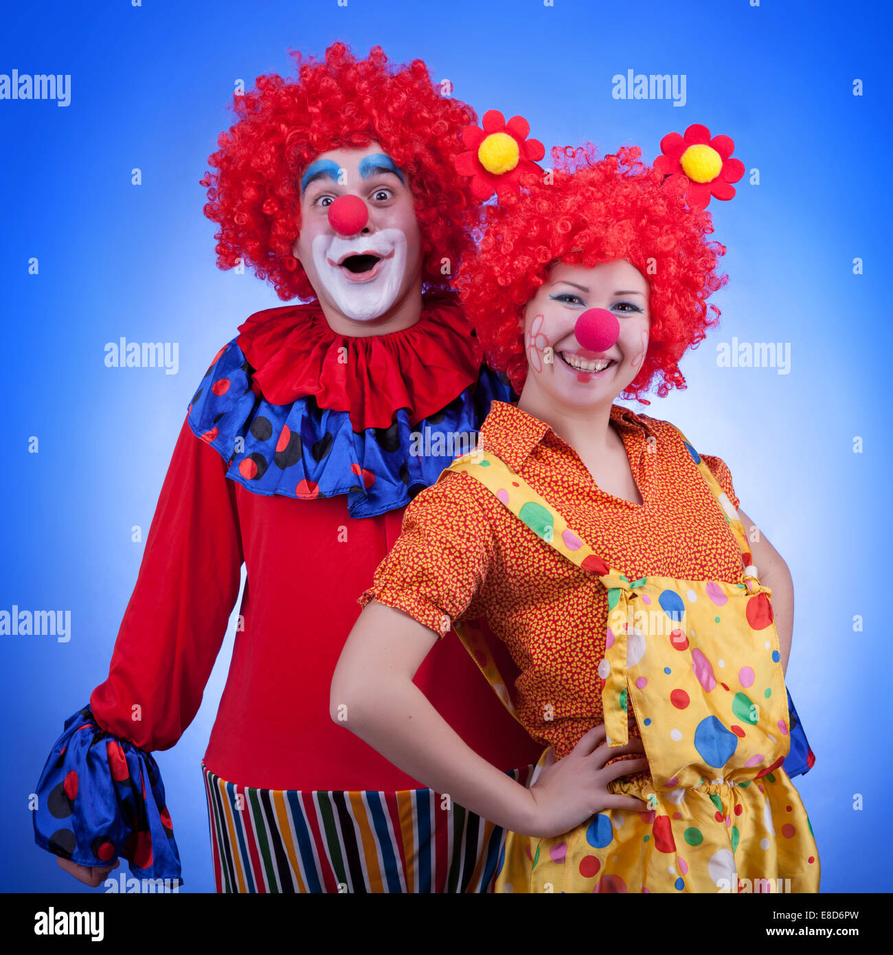 Clown couple in costumes on blue background. Studio professional ...