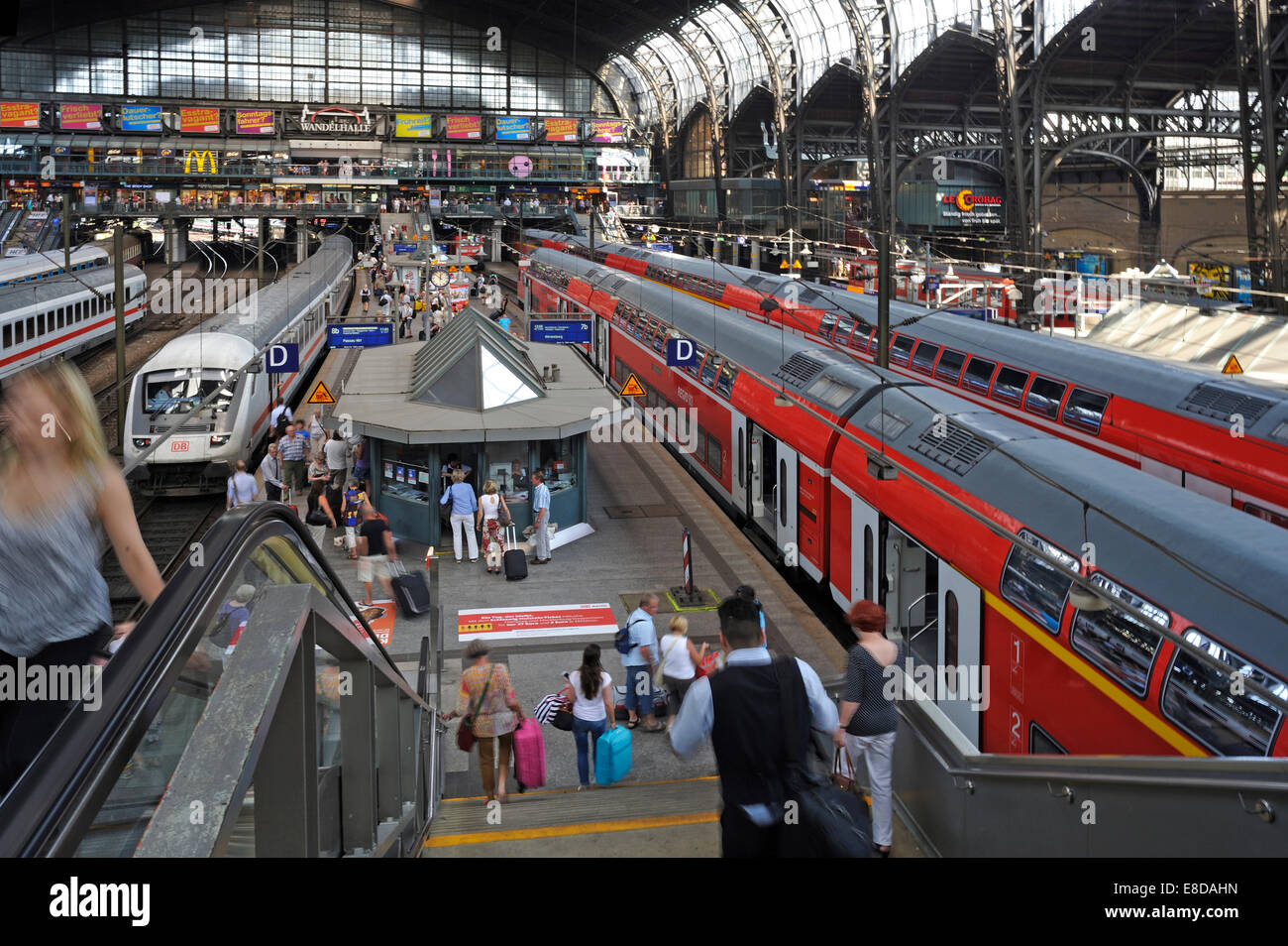 Station concourse with travelers, and local and long-distance trains ...