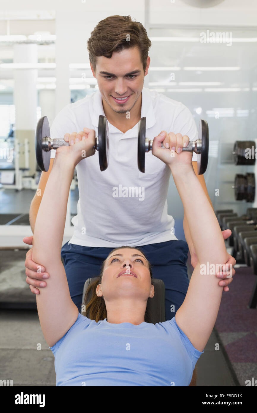 Personal trainer helping client lift dumbbells Stock Photo - Alamy
