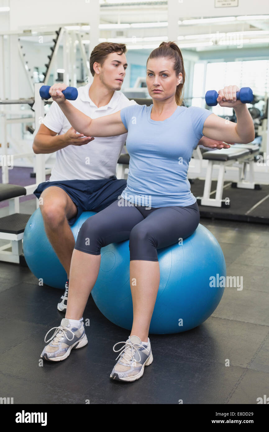 Personal trainer working with client on exercise ball Stock Photo - Alamy