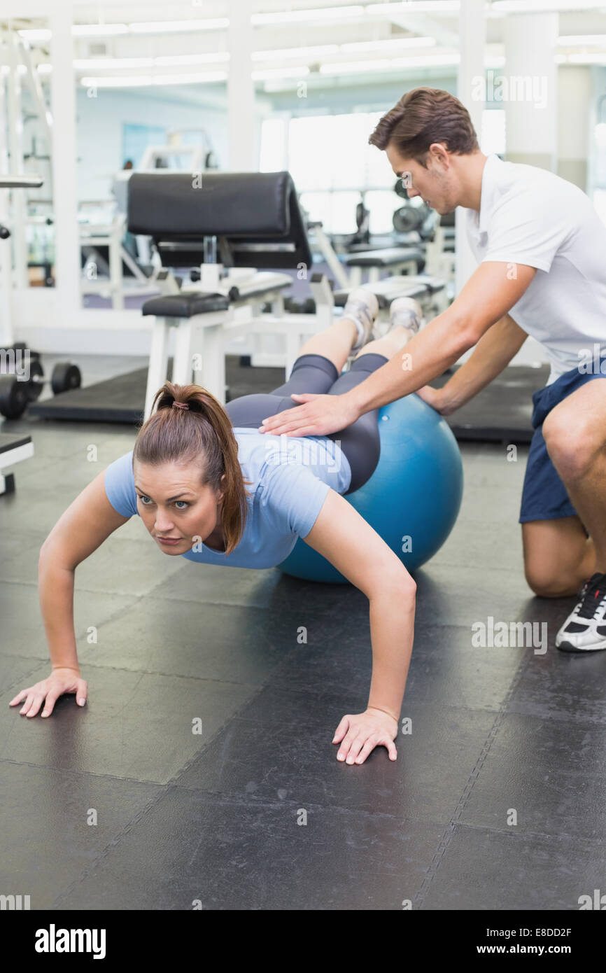Personal trainer working with client on exercise ball Stock Photo - Alamy