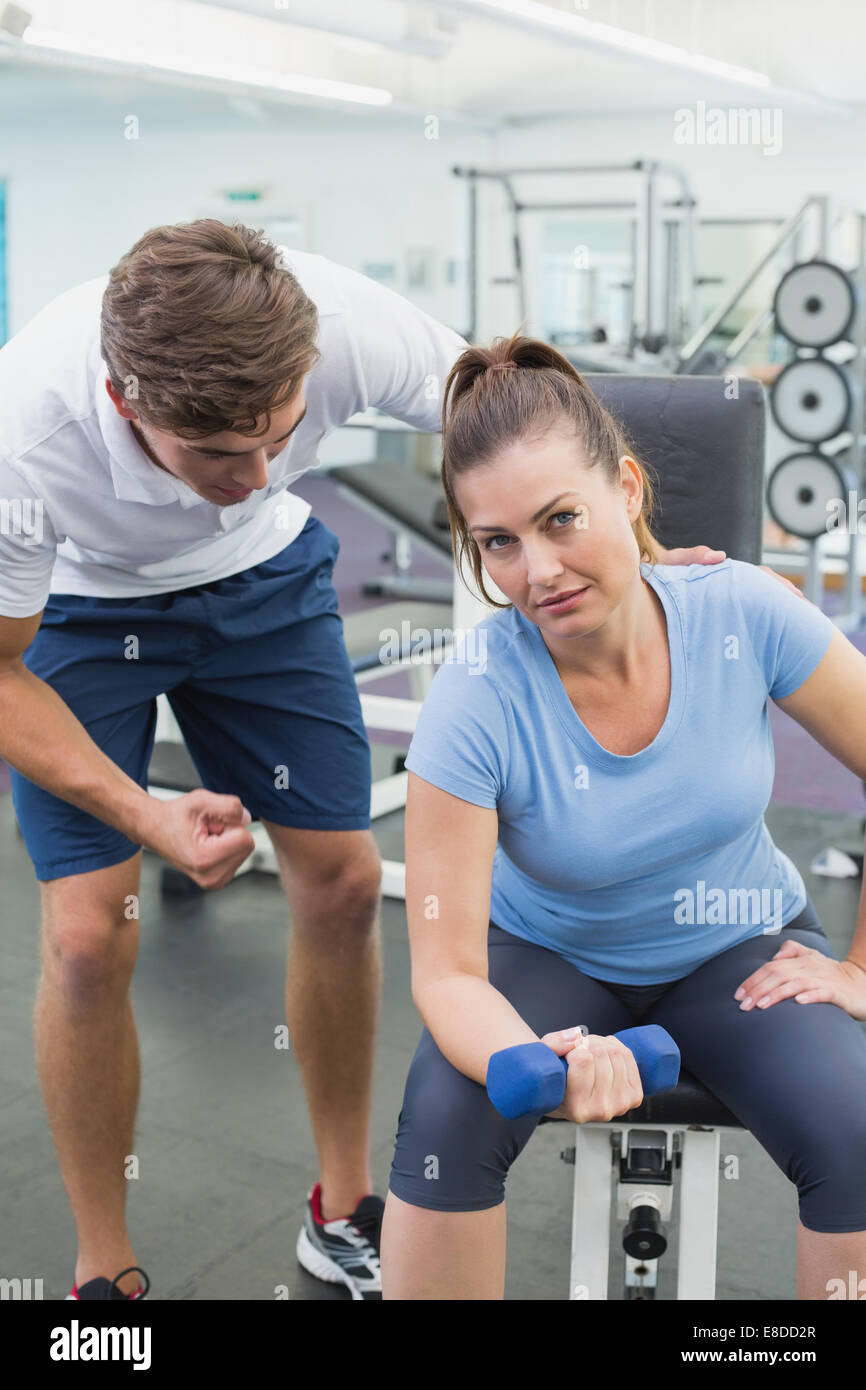 Personal trainer helping client lift dumbbell Stock Photo - Alamy