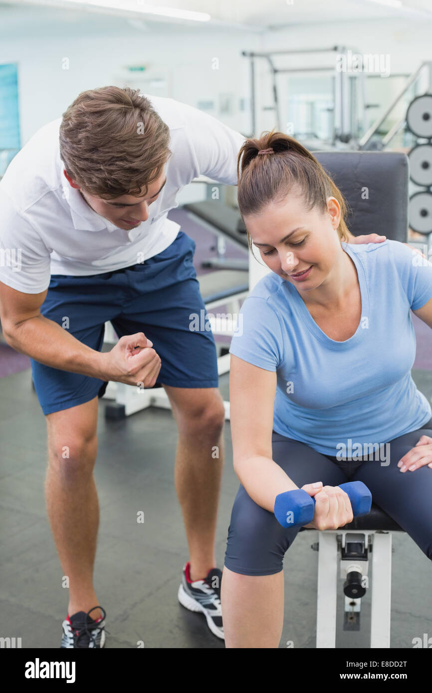 Personal trainer helping client lift dumbbell Stock Photo - Alamy