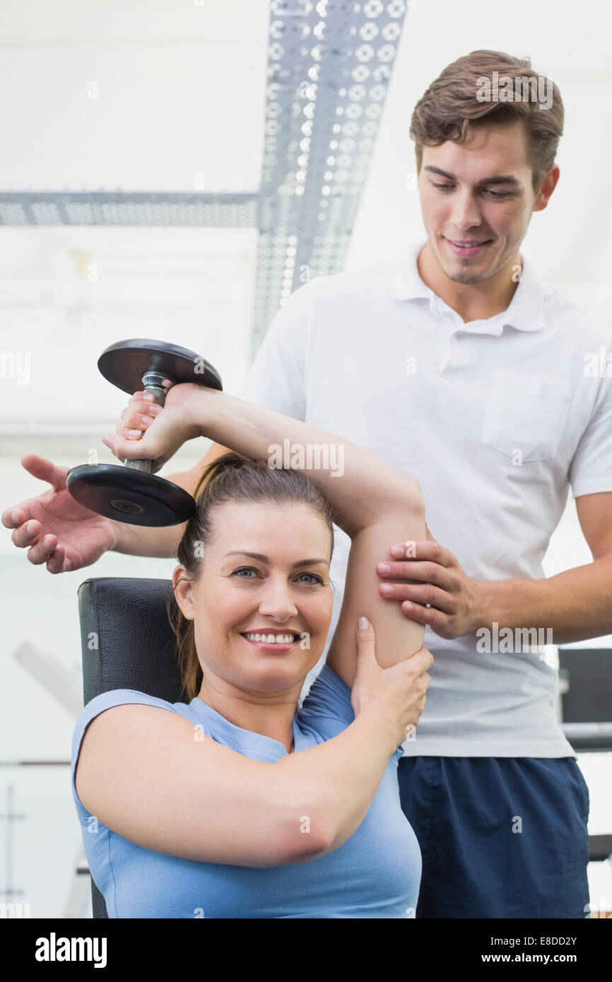 Personal trainer helping client lift dumbbell Stock Photo - Alamy