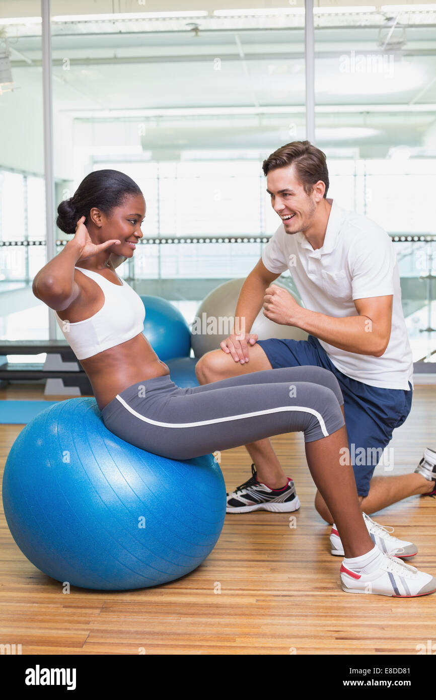 Personal trainer working with client on exercise ball Stock Photo - Alamy