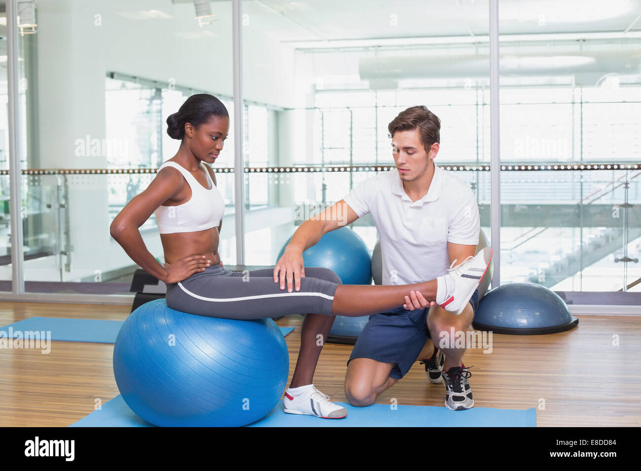 Personal trainer working with client on exercise ball Stock Photo - Alamy