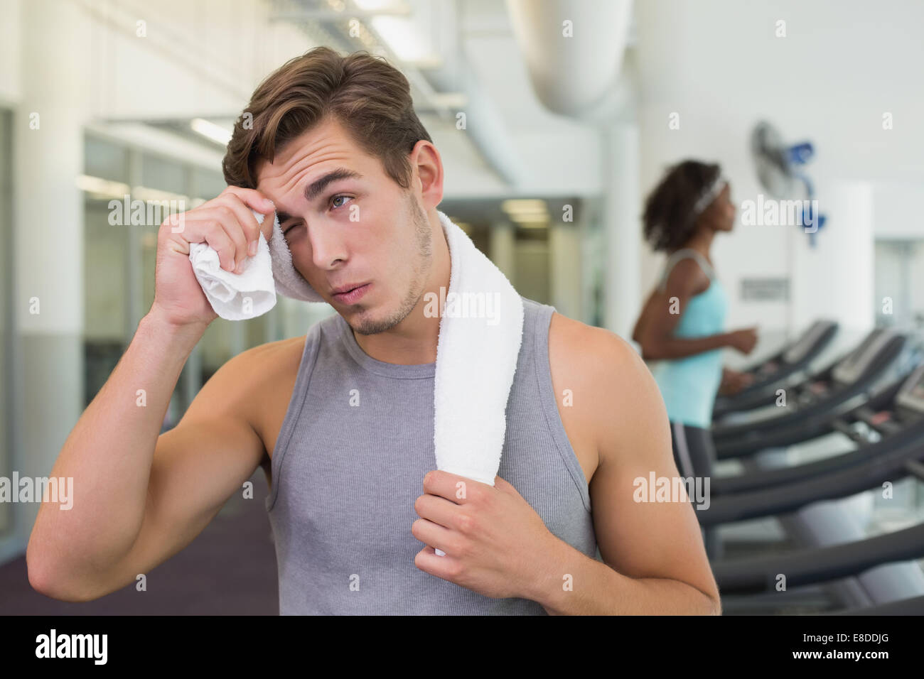 Handsome man wiping his forehead beside treadmills Stock Photo - Alamy