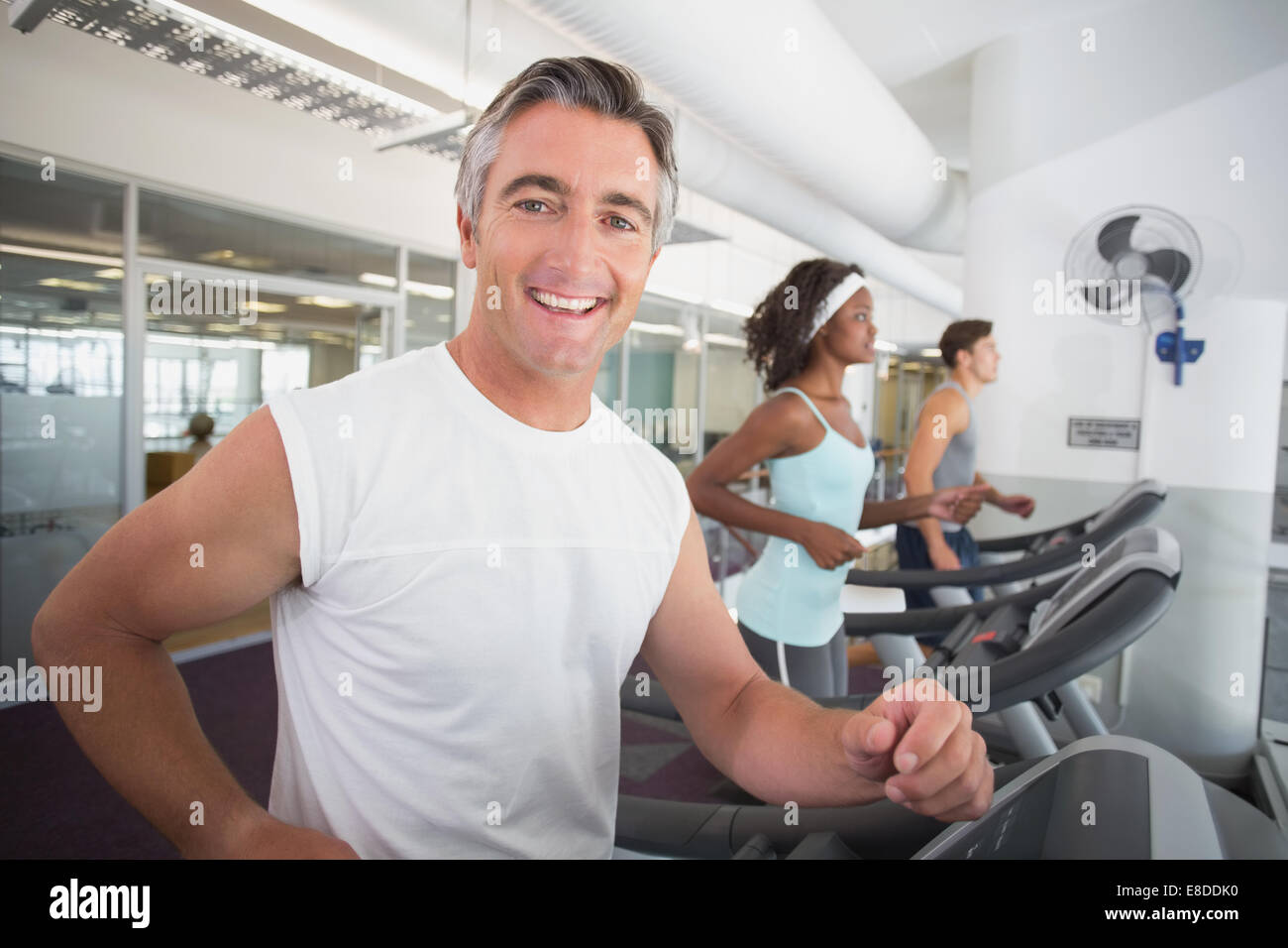 Fit man running on treadmill smiling at camera Stock Photo - Alamy