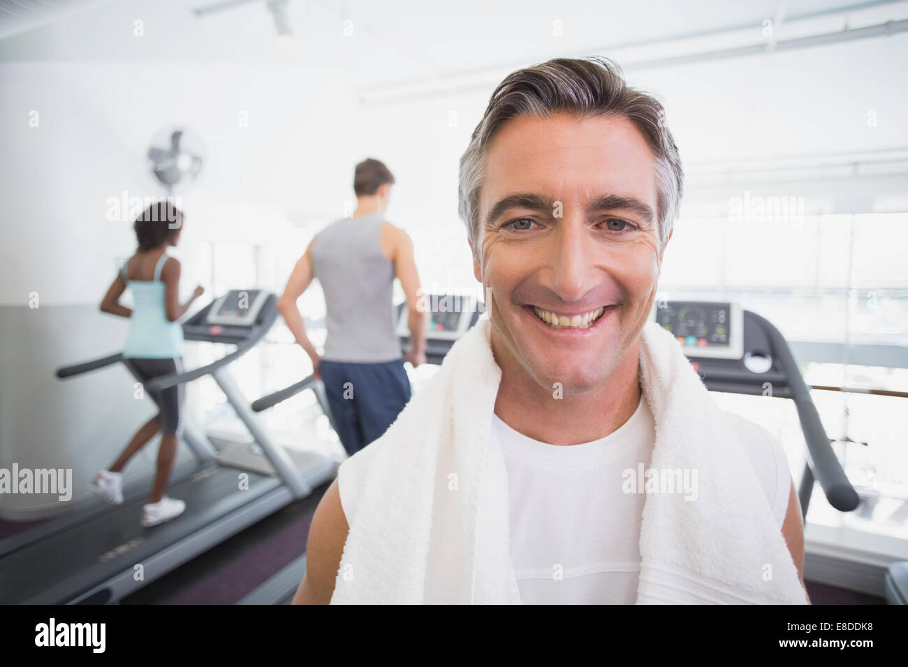 Fit man smiling at camera beside treadmills Stock Photo - Alamy