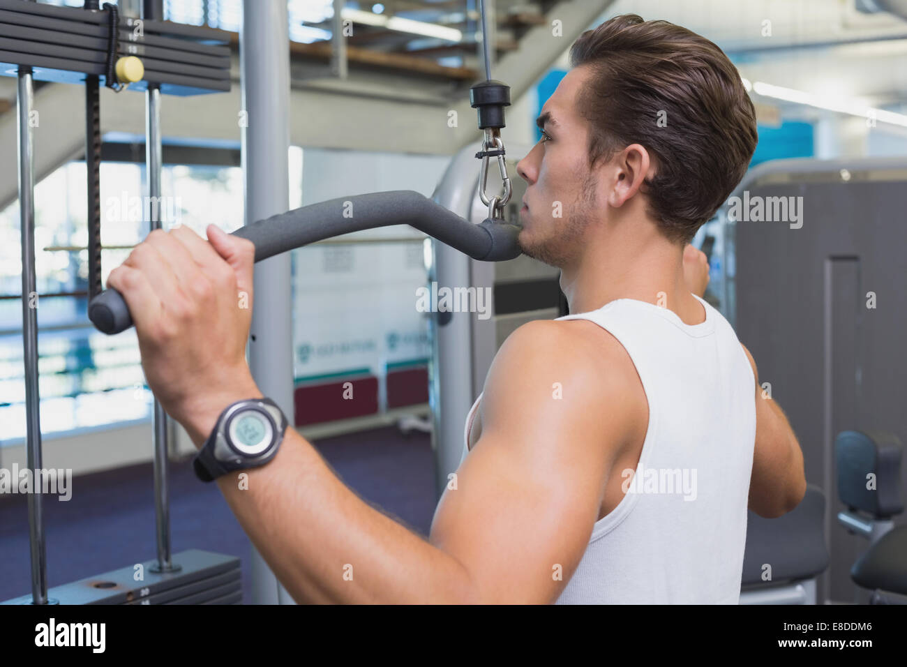 Strong man using weights machine for arms Stock Photo - Alamy