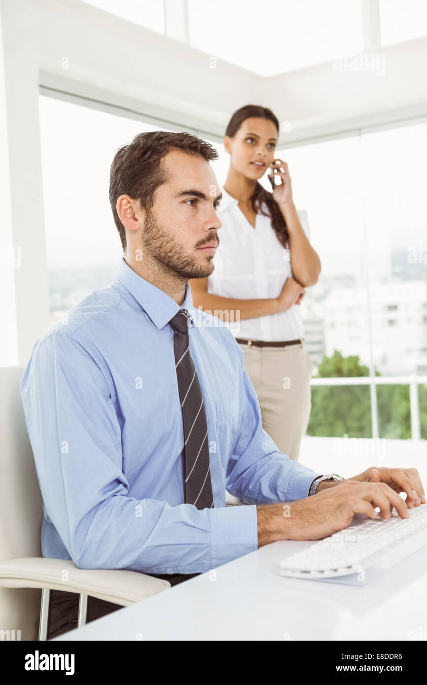 Businessman using computer while woman on call Stock Photo - Alamy