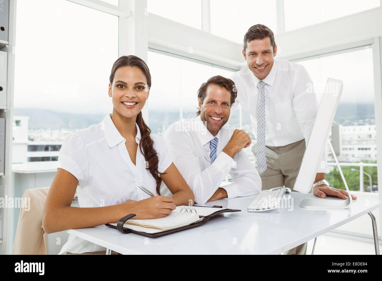 Three smiling business people at office desk Stock Photo - Alamy