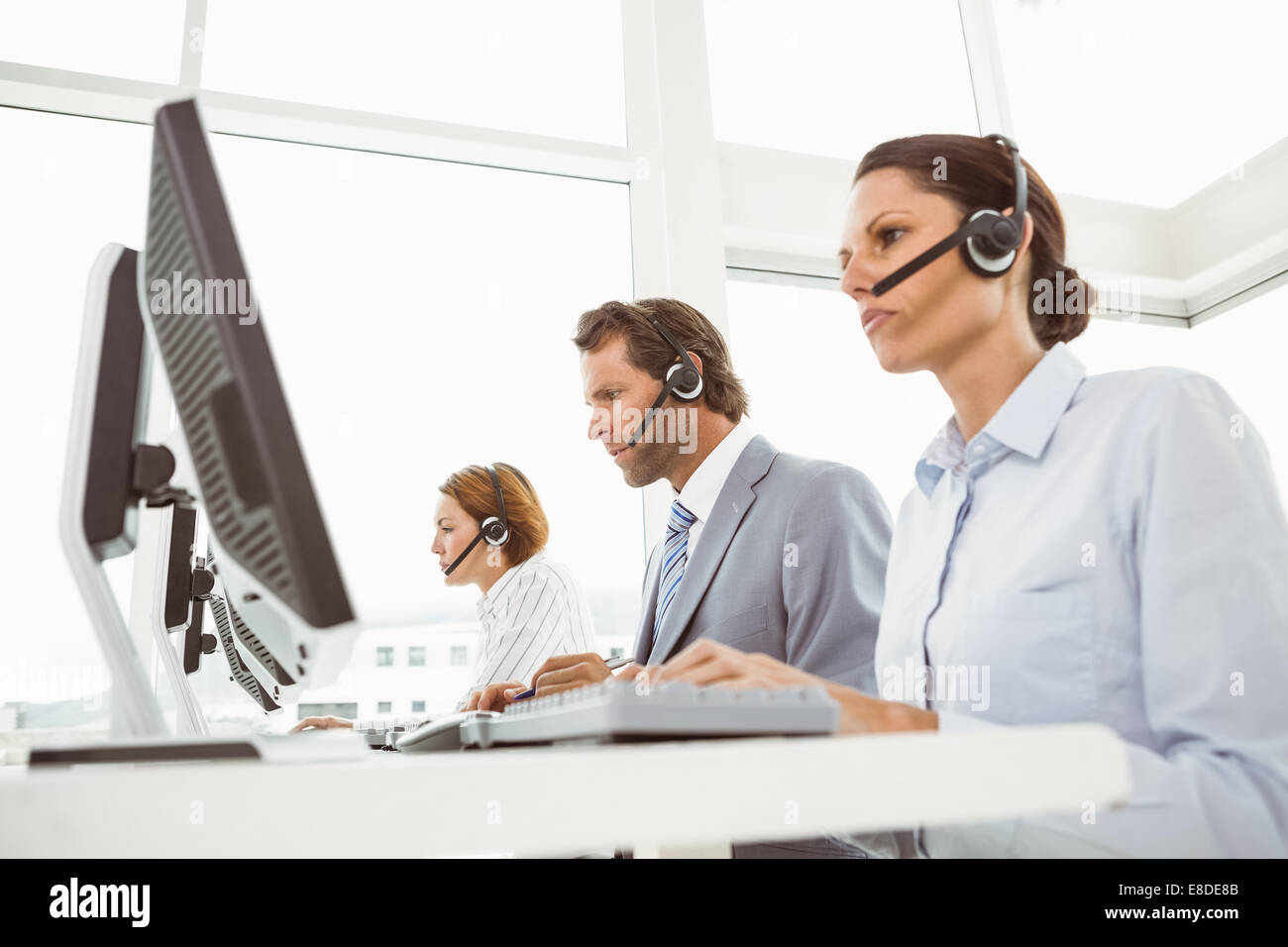 Business people with headsets using computers in office Stock Photo - Alamy
