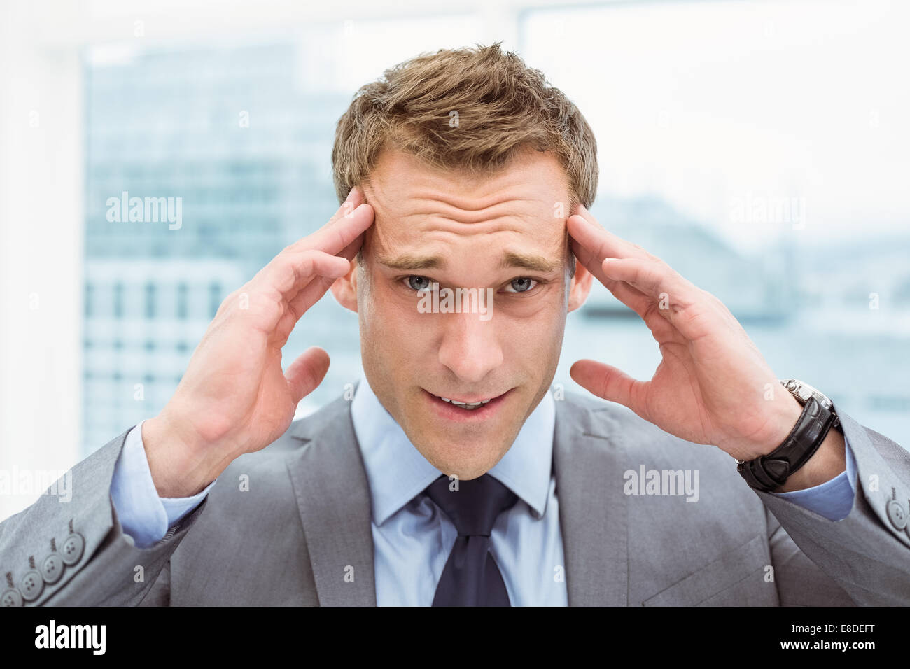 Businessman with severe headache at office Stock Photo - Alamy