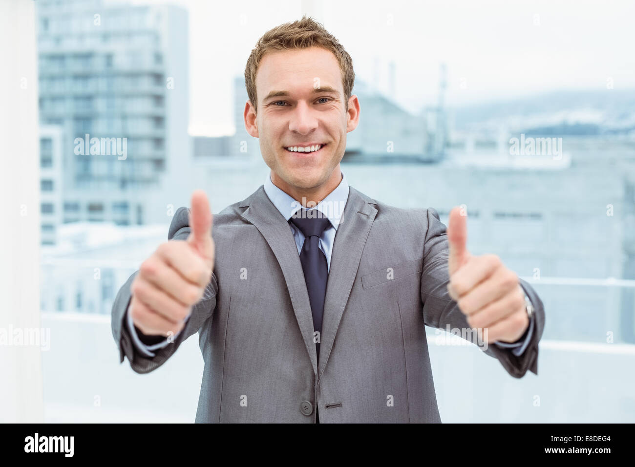 Businessman gesturing thumbs up in office Stock Photo - Alamy