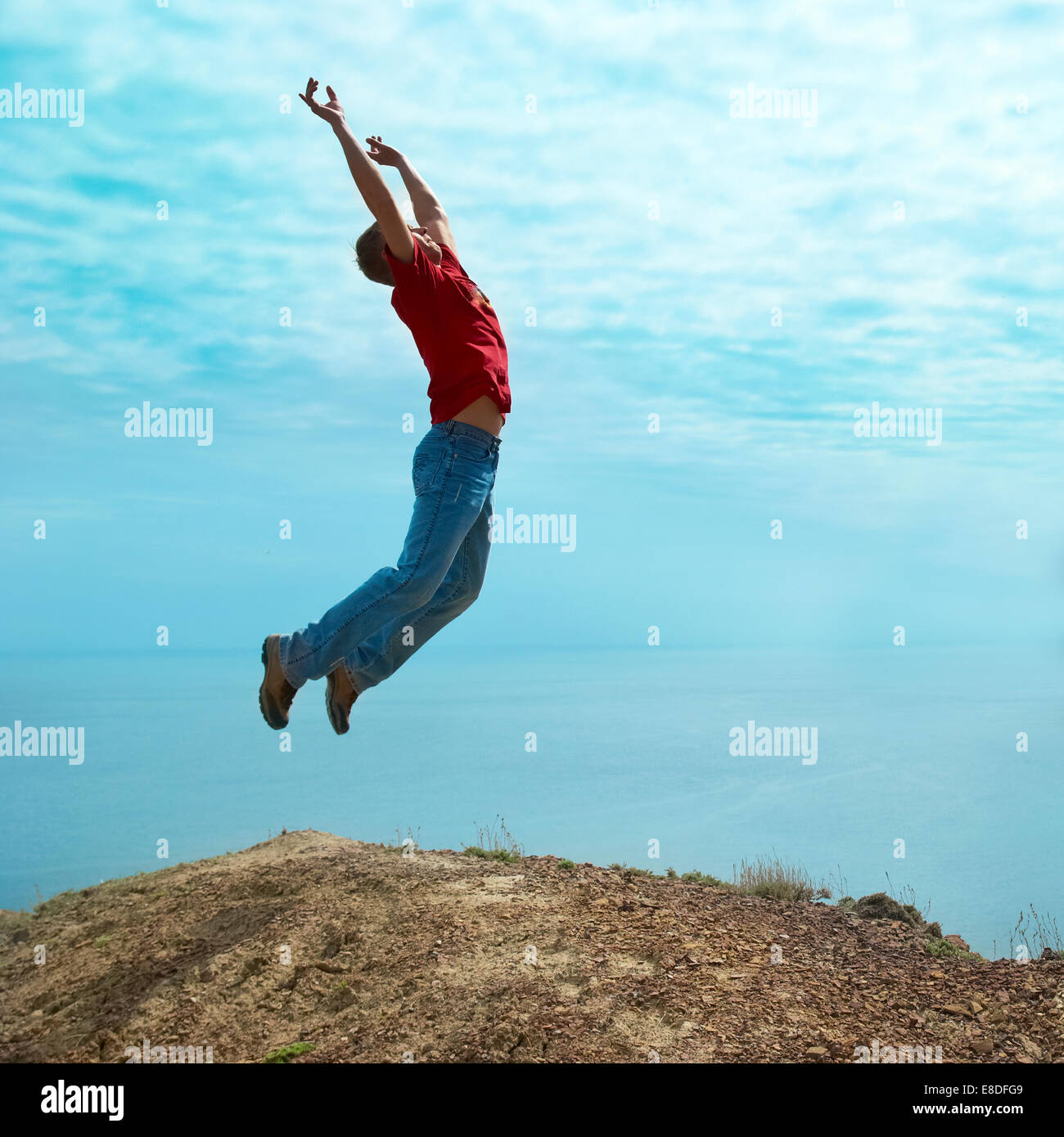 Man jumping cliff against sea and mountain with blue sky Stock Photo ...