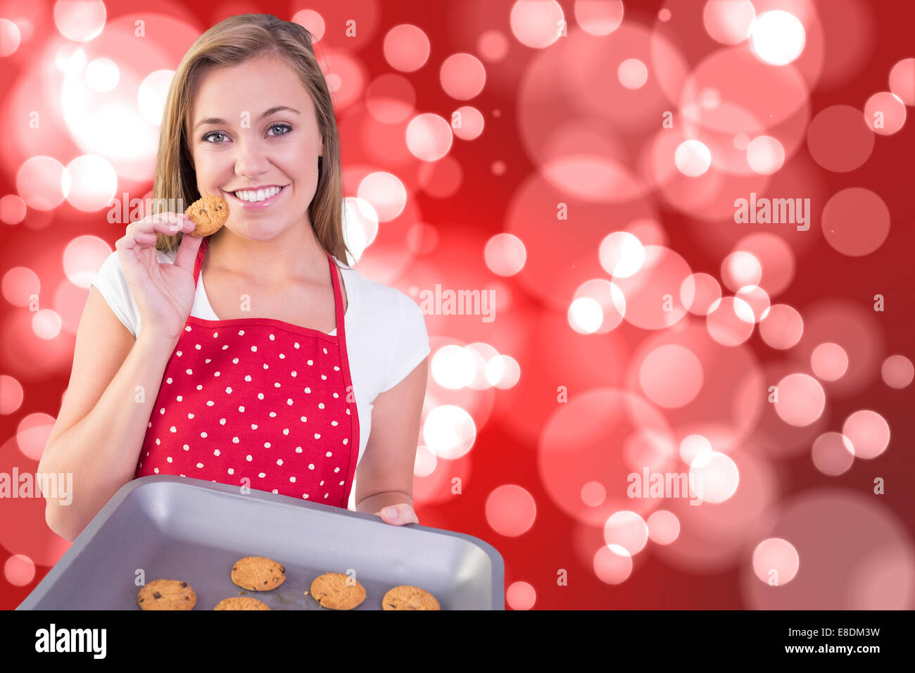 Composite image of pretty homemaker showing hot cookies Stock Photo - Alamy