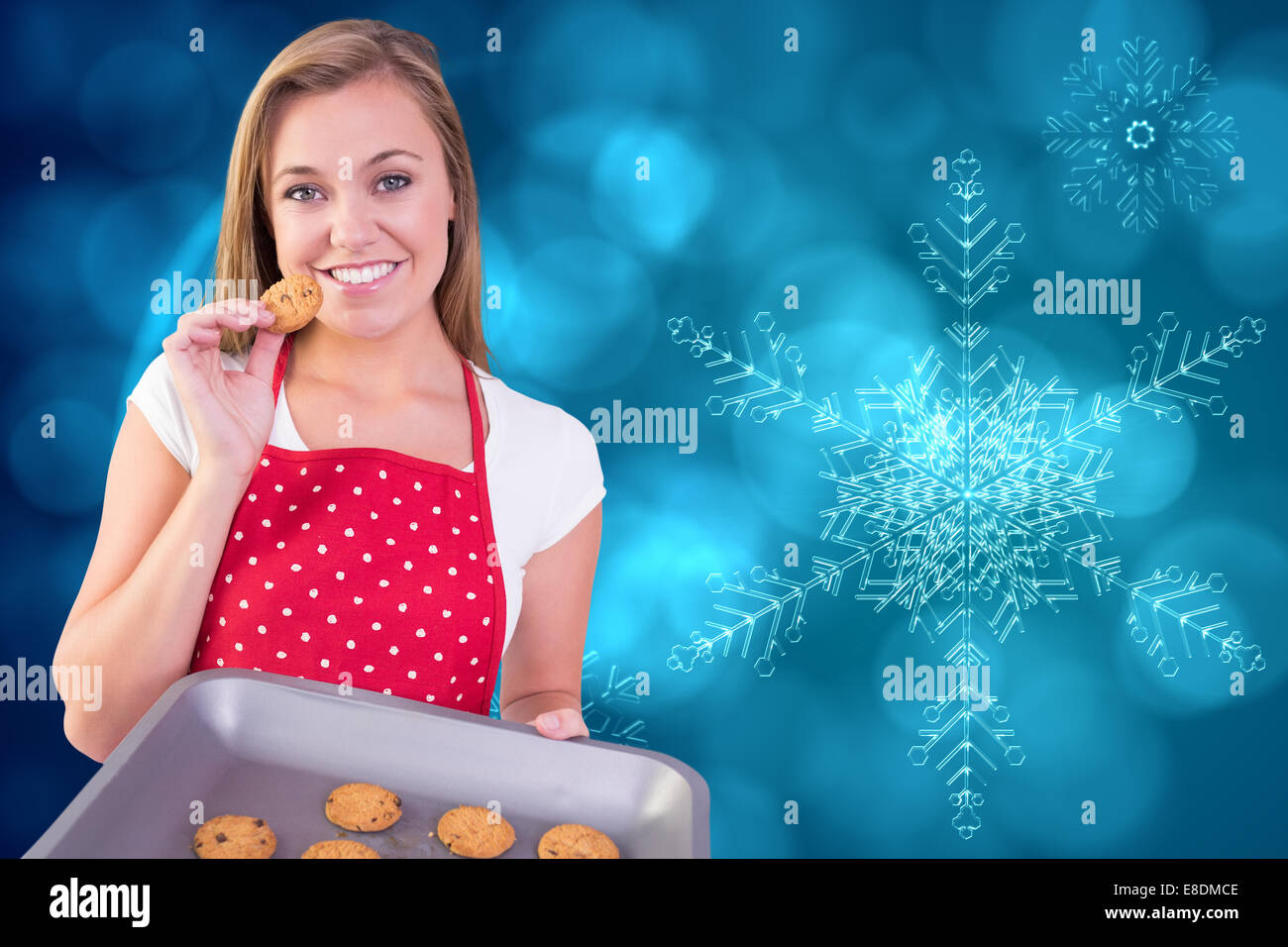 Composite image of pretty homemaker showing hot cookies Stock Photo - Alamy