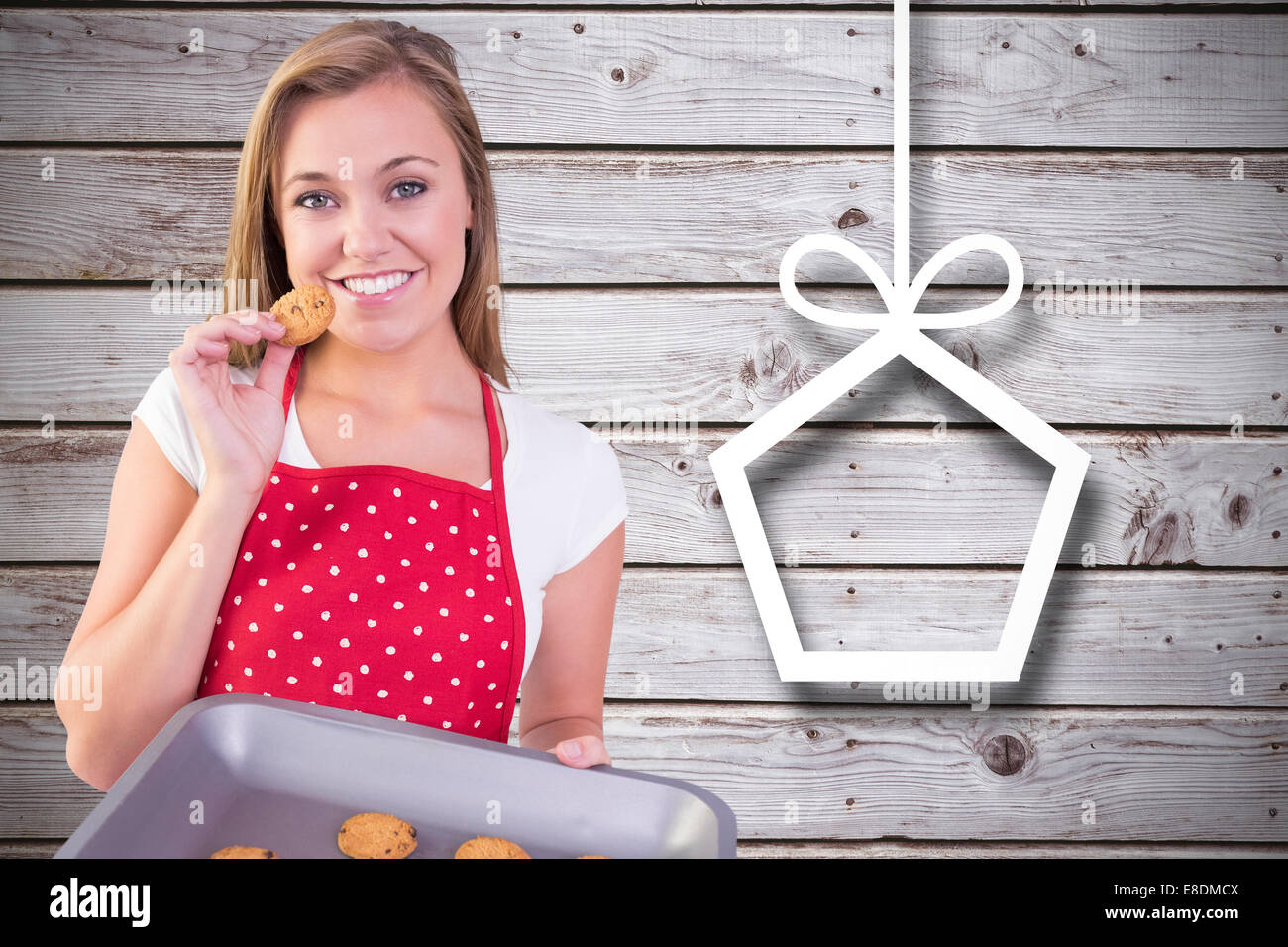 Composite image of pretty homemaker showing hot cookies Stock Photo - Alamy