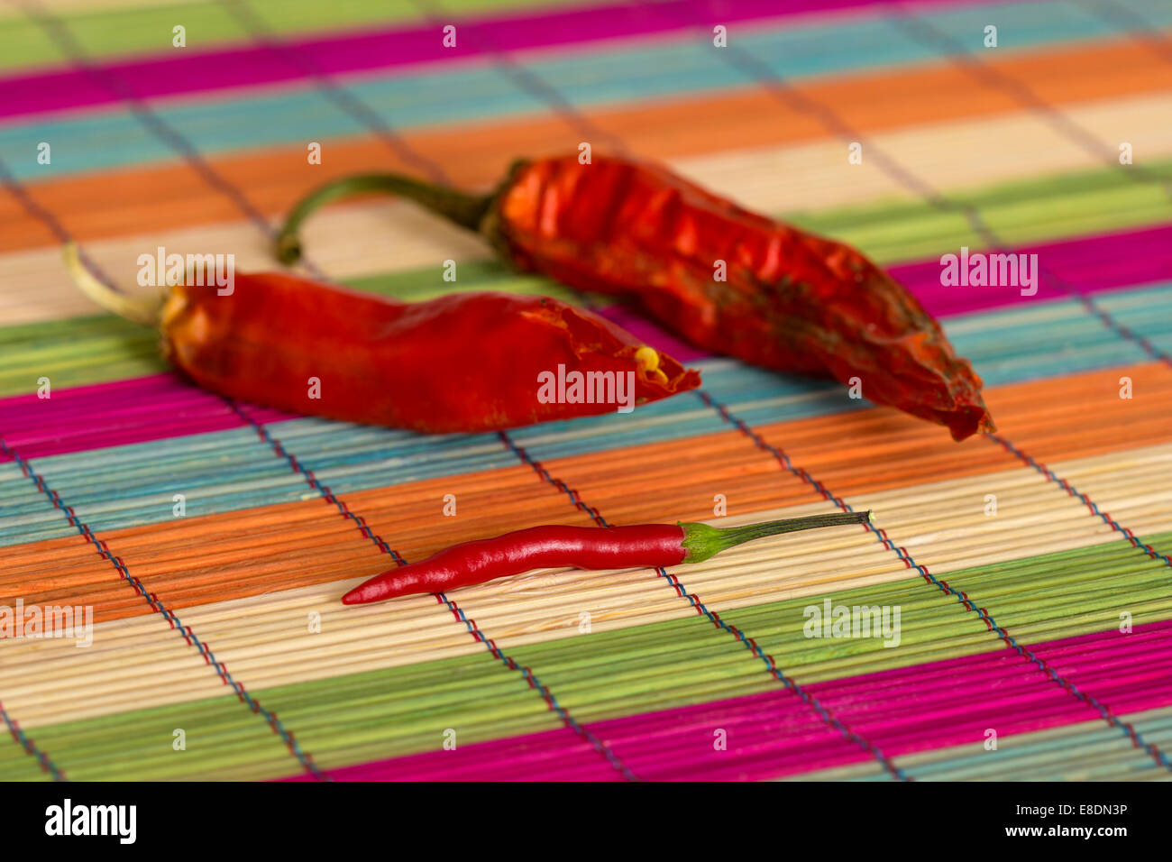 three red chillies on a decorative background Stock Photo - Alamy