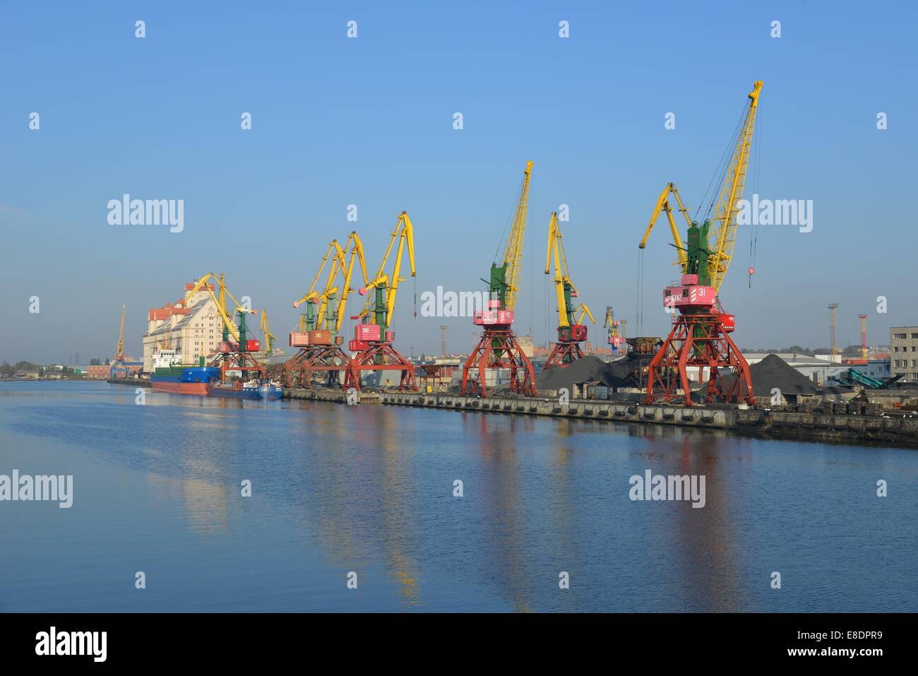 Cargo ship and big industrial harbor crane stands on the river coast in ...