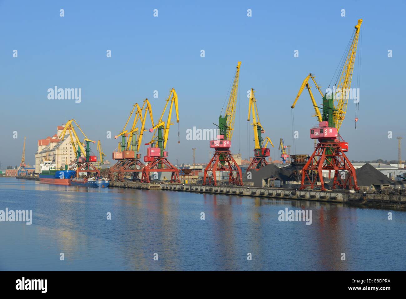 Cargo ship and big industrial harbor crane stands on the river coast in ...