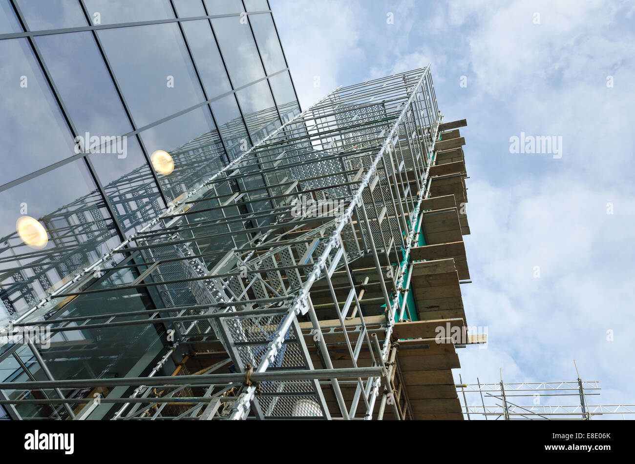 contrasting scaffolding stand alone tower against new modern highly ...