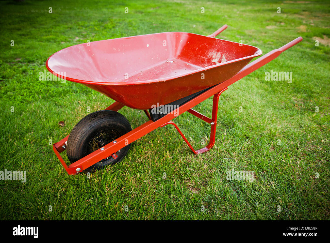 Red wheelbarrow in the middle of the lawn Stock Photo - Alamy