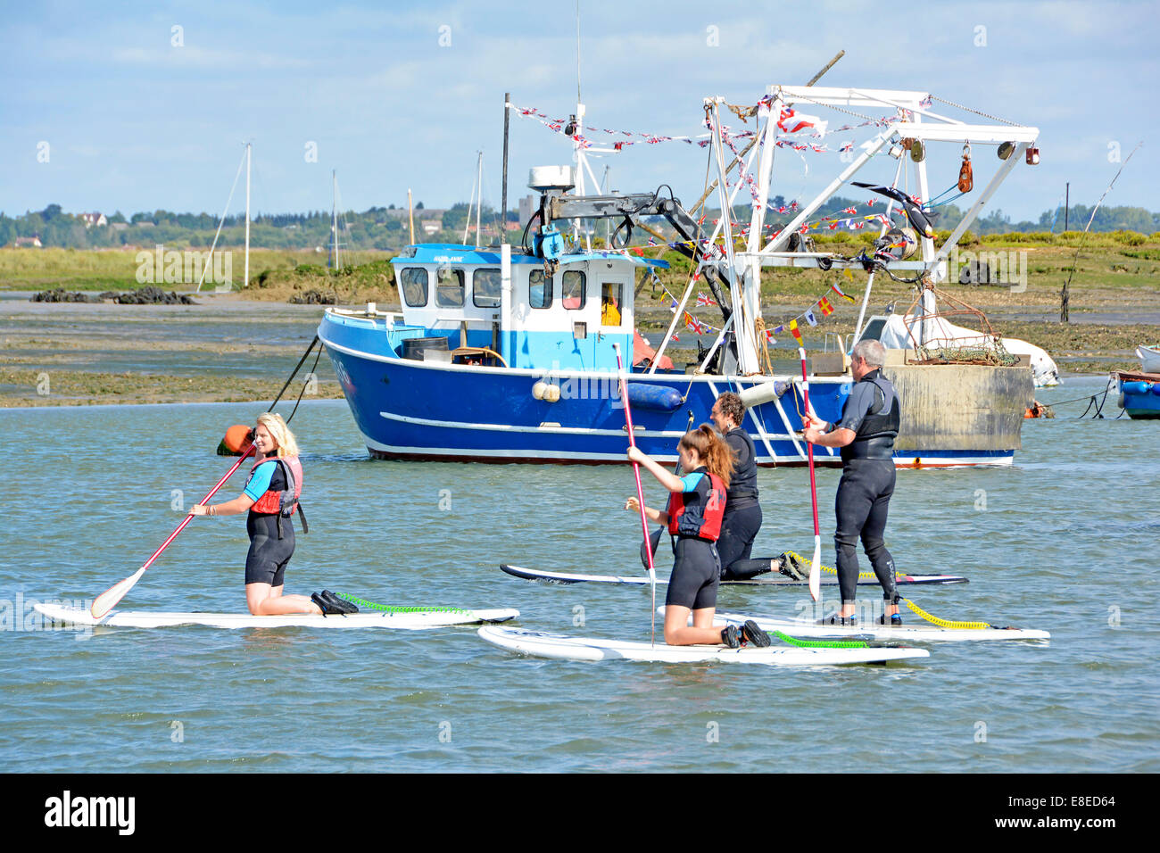 Group of people paddle boarding by kneeling on the board with one man ...
