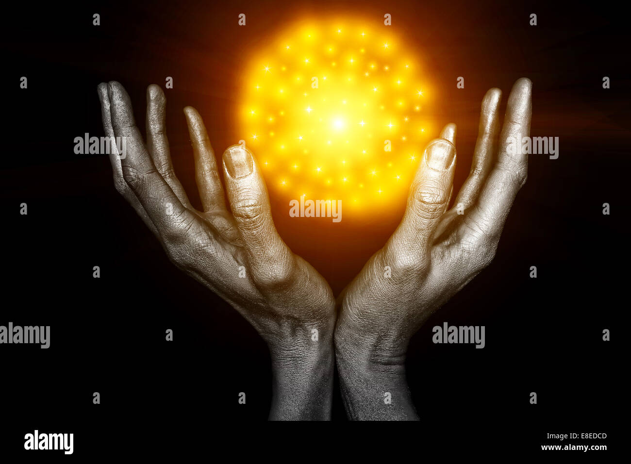 Silvery male hands with a yellow energy ball on a black background ...