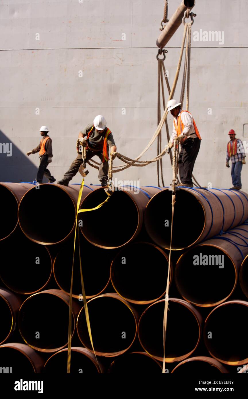 Workers Offloading Pipe from Cargo Ship Stock Photo - Alamy