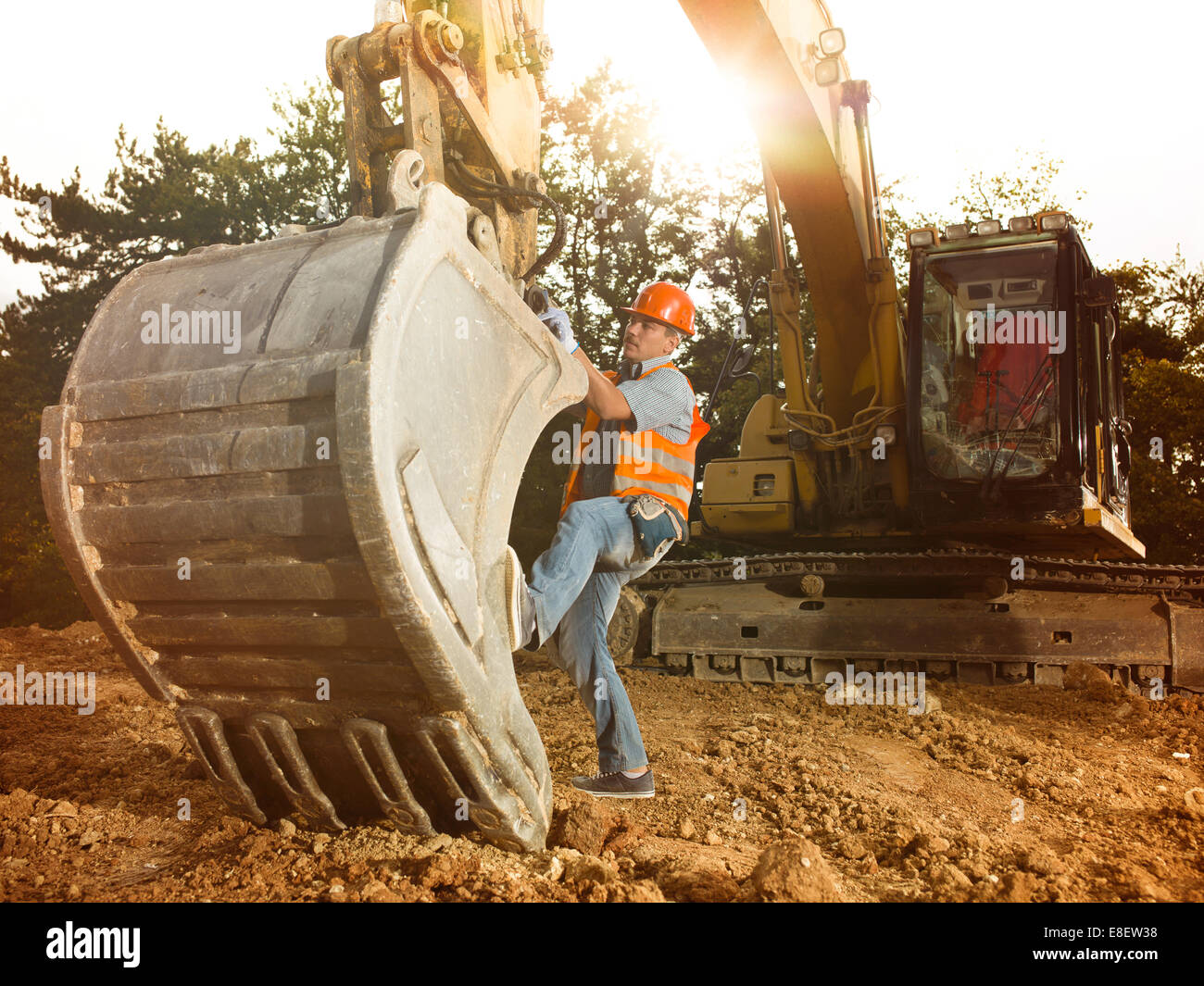 male engineer standing next to excavator on construction site outdoors ...