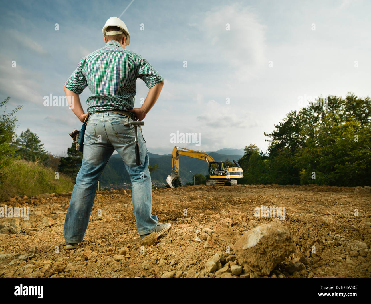 back view of male engineer standing on construction site evaluating the ...