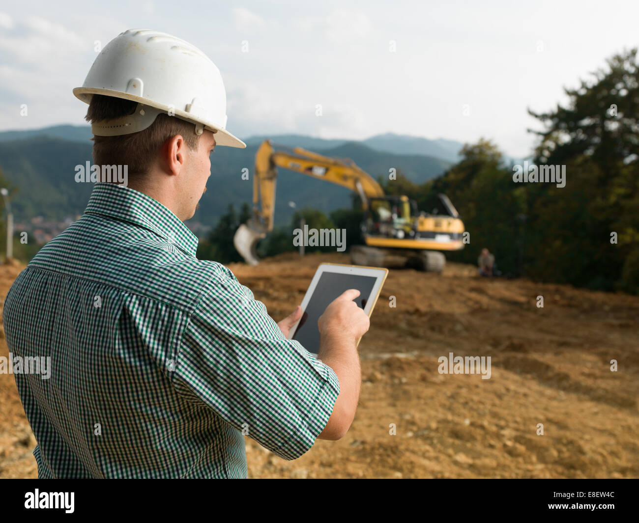 back view of caucasian engineer standing on construction site checking ...
