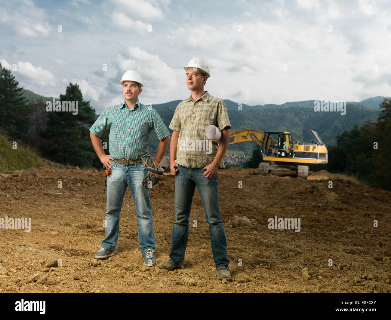 two young caucasian engineers standing on construction site outdoors ...